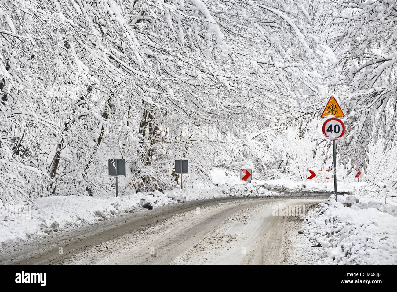 Dangerous snow covered road with road signs Stock Photo - Alamy