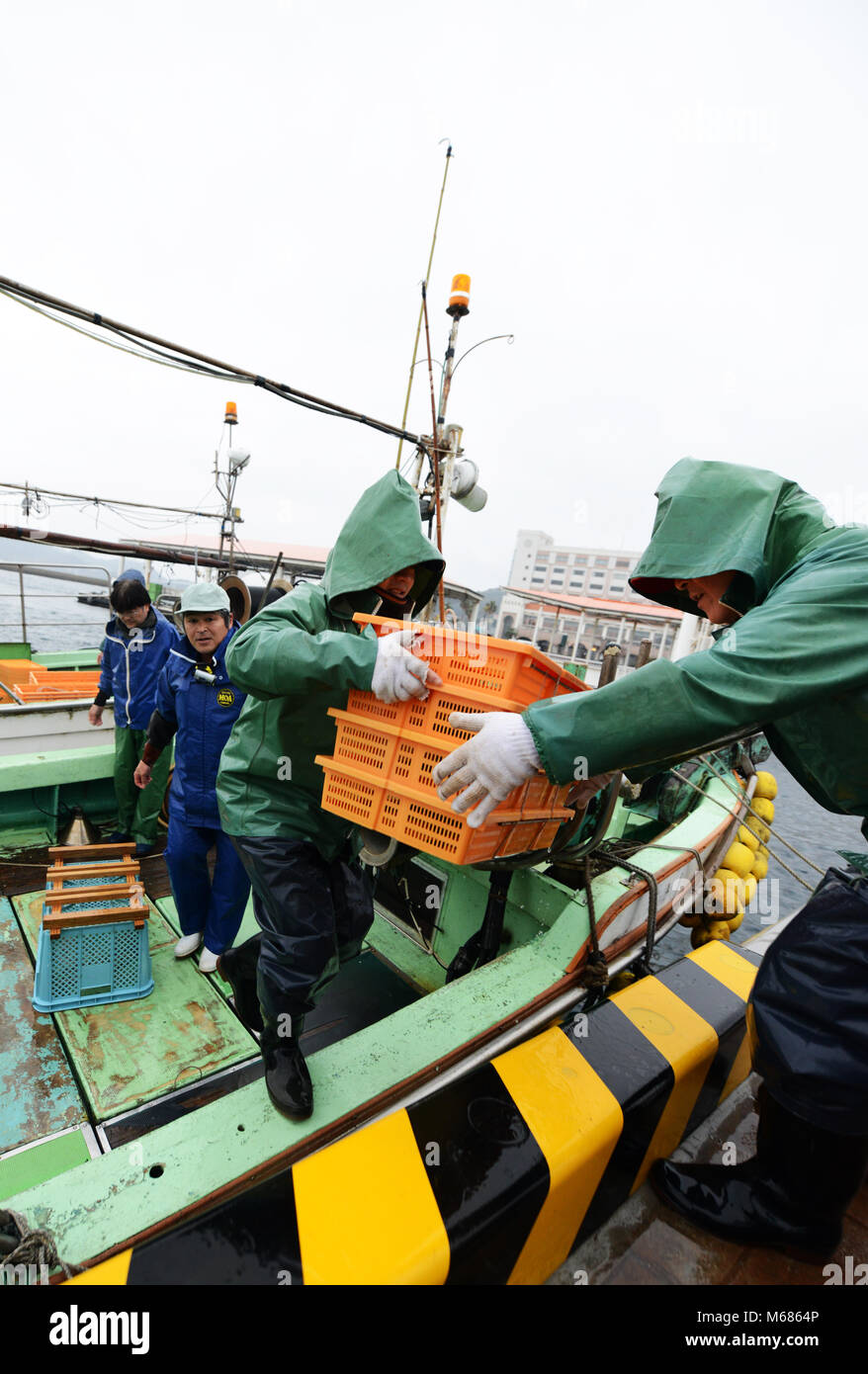 Japanese fishermen transferring the fresh fish from their fishing boat ...