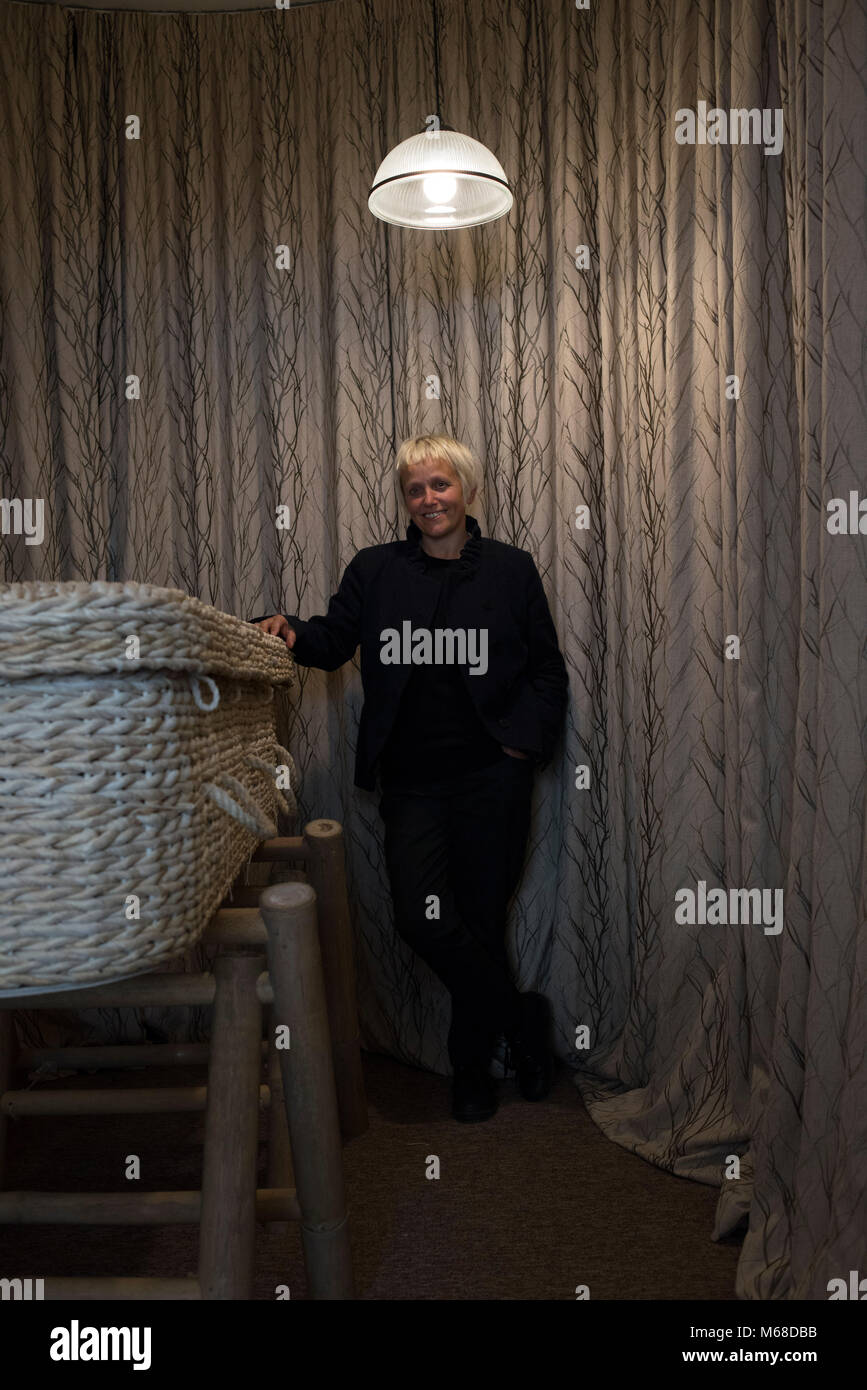 a friendly young funeral director / undertaker stands by a wicker ...