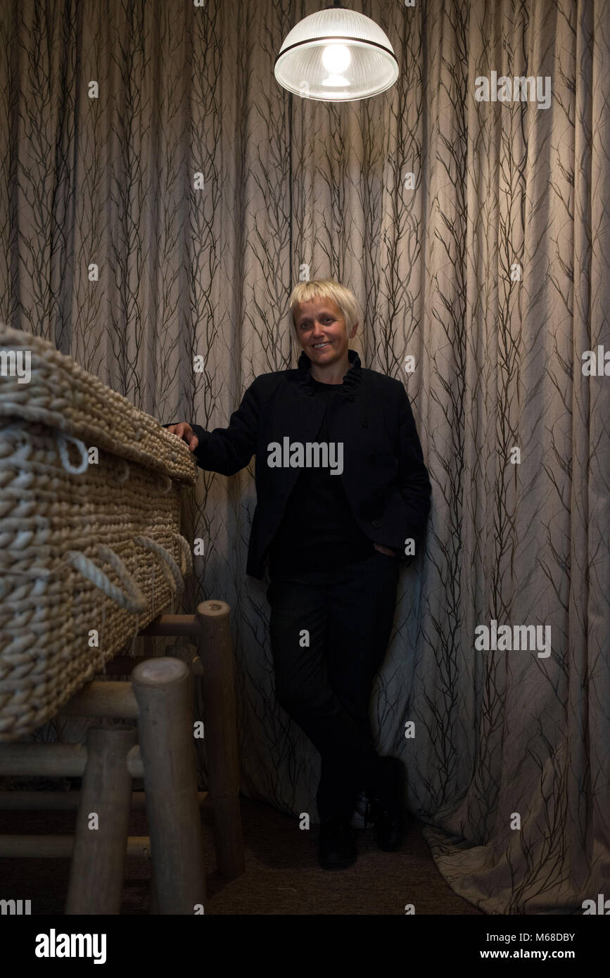 a friendly young funeral director / undertaker stands by a wicker ...