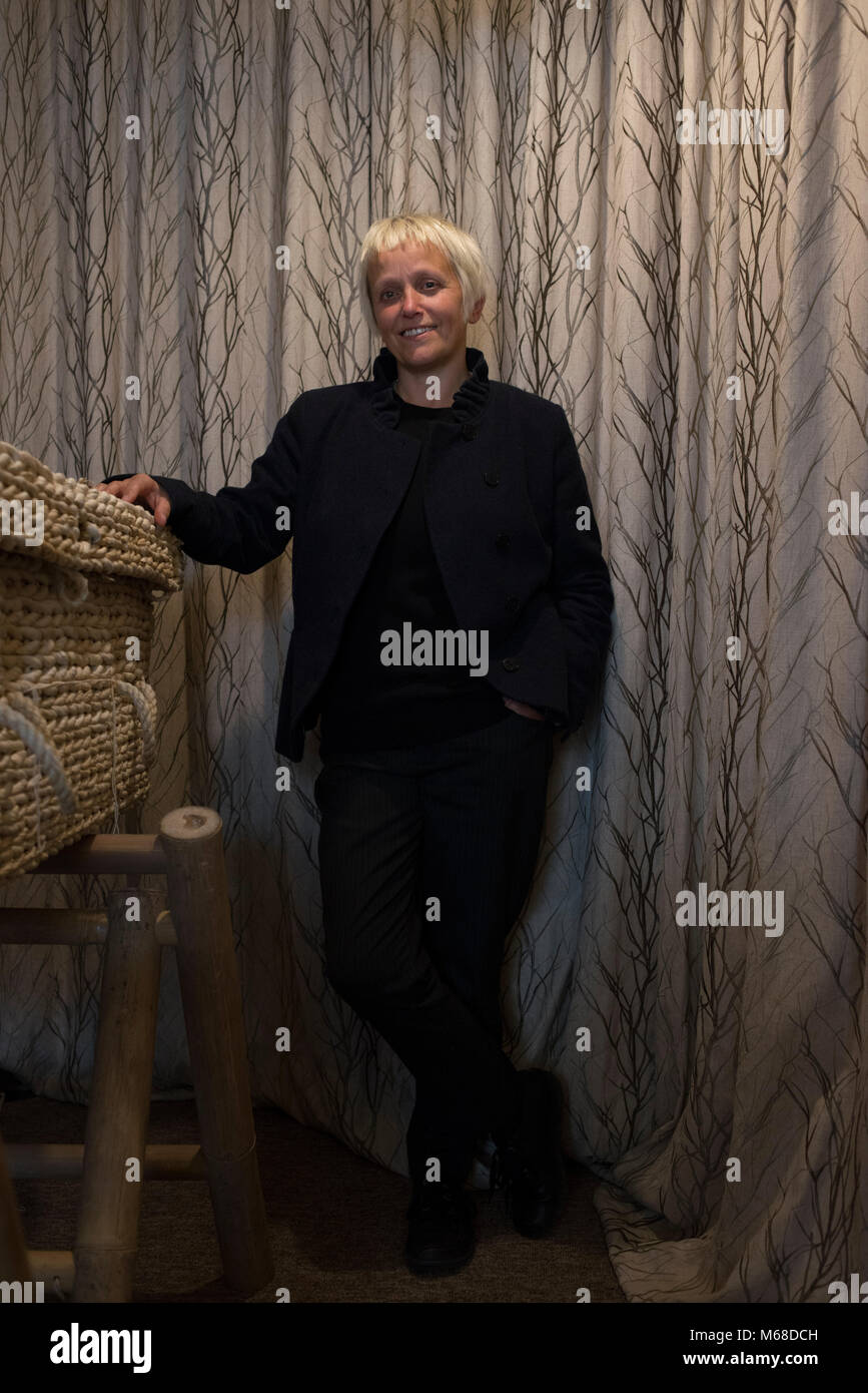 a friendly young funeral director / undertaker stands by a wicker ...
