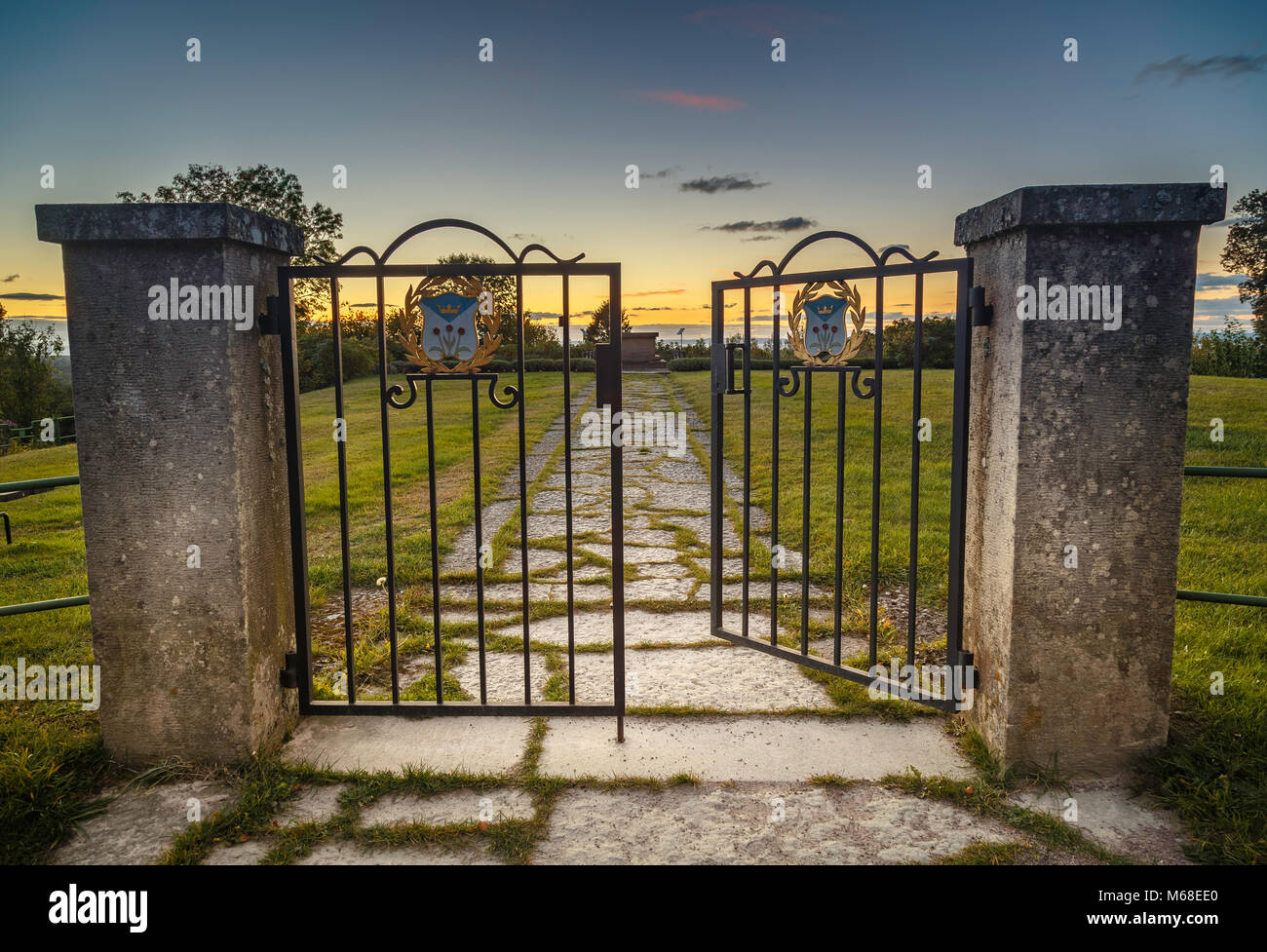 an open iron gate with the sunset as background Stock Photo - Alamy