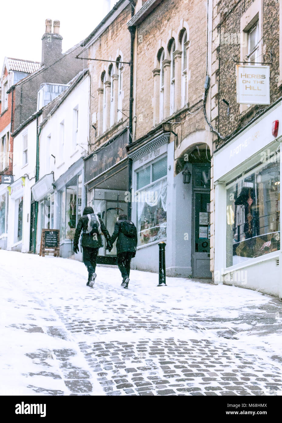 A couple walk up Catherine Hill, Frome, Somerset, England after a fresh ...
