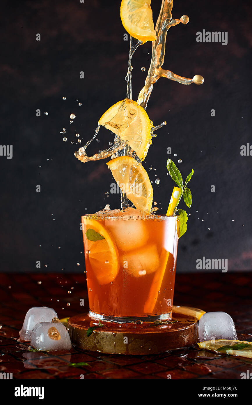 Iced lemon tea on dark background in glass and flying in air ...