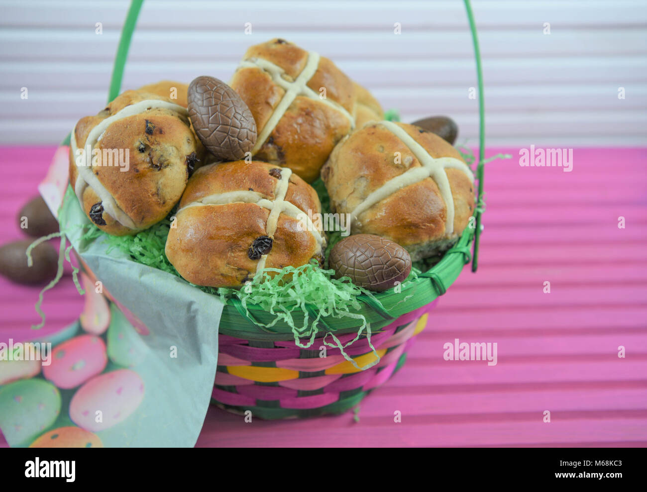 Easter food in a basket with hot cross buns and chocolate Easter eggs ...