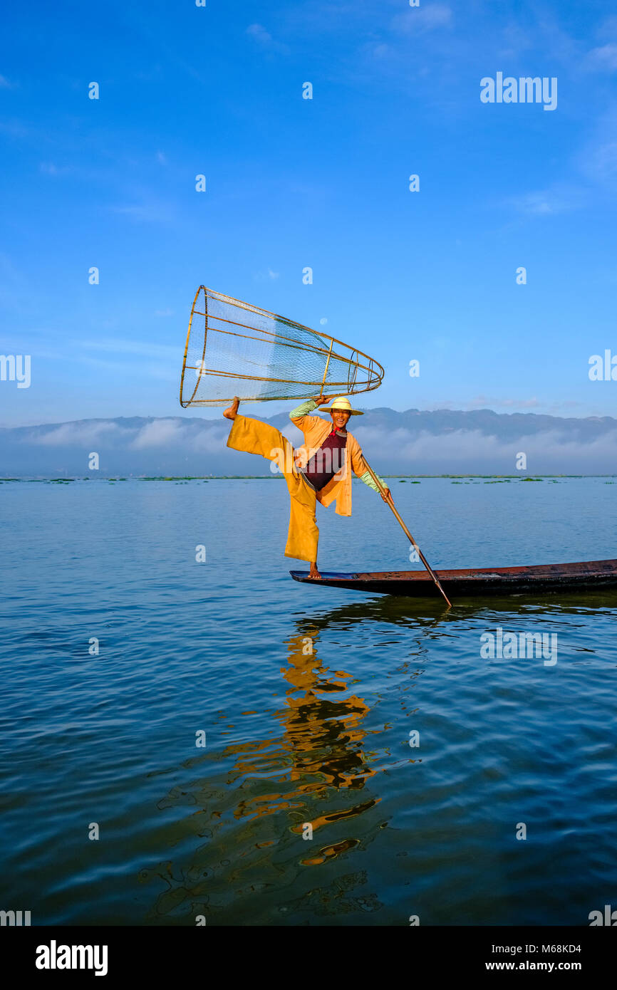 A fisherman, standing on his boat, posing, is fishing the traditional ...