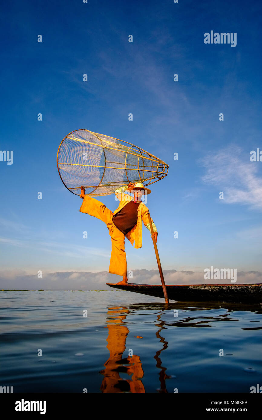 A fisherman, standing on his boat, posing, is fishing the traditional ...