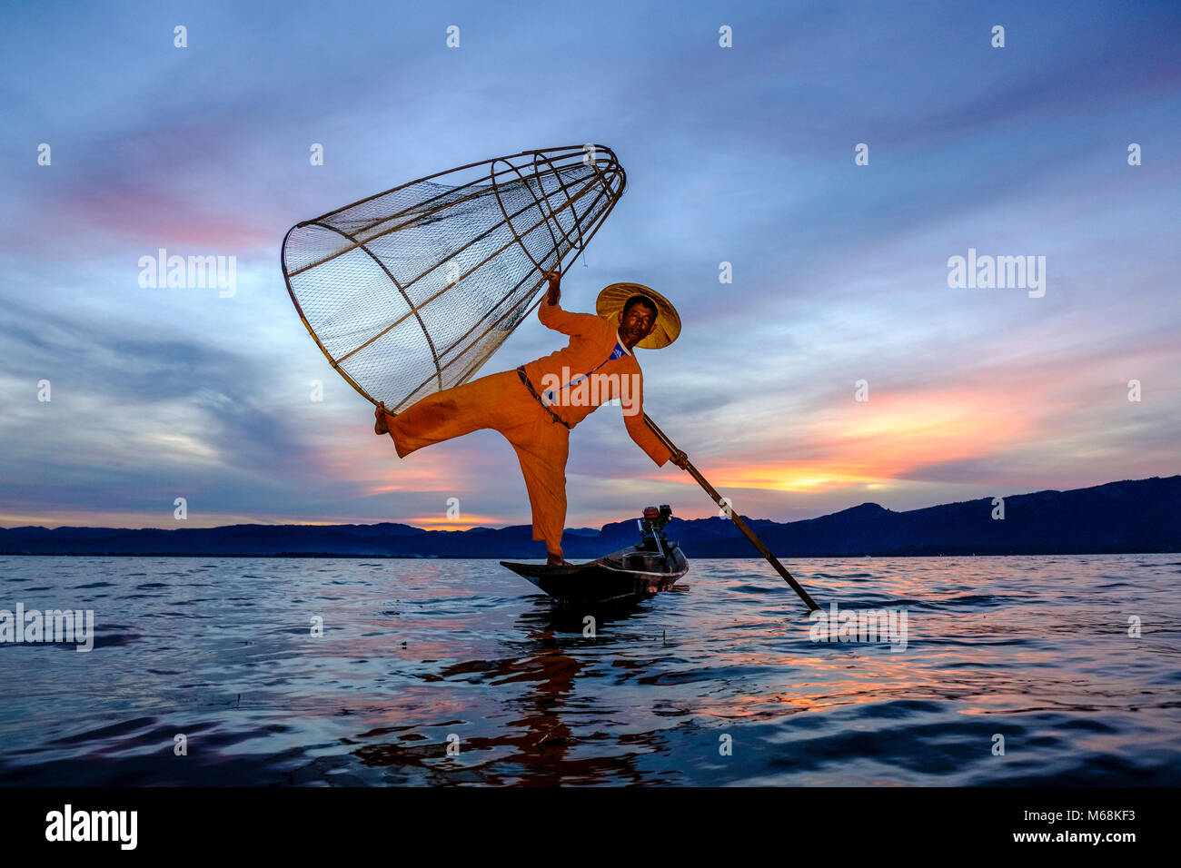 A fisherman, standing on his boat, posing, is fishing the traditional ...