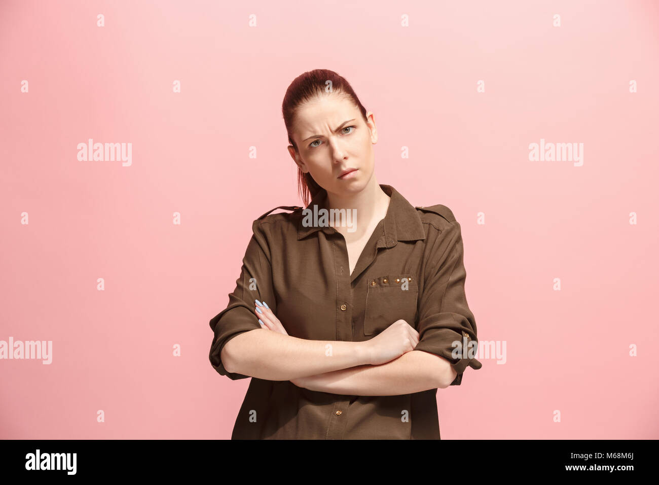 The serious business woman standing and looking at camera against pink ...