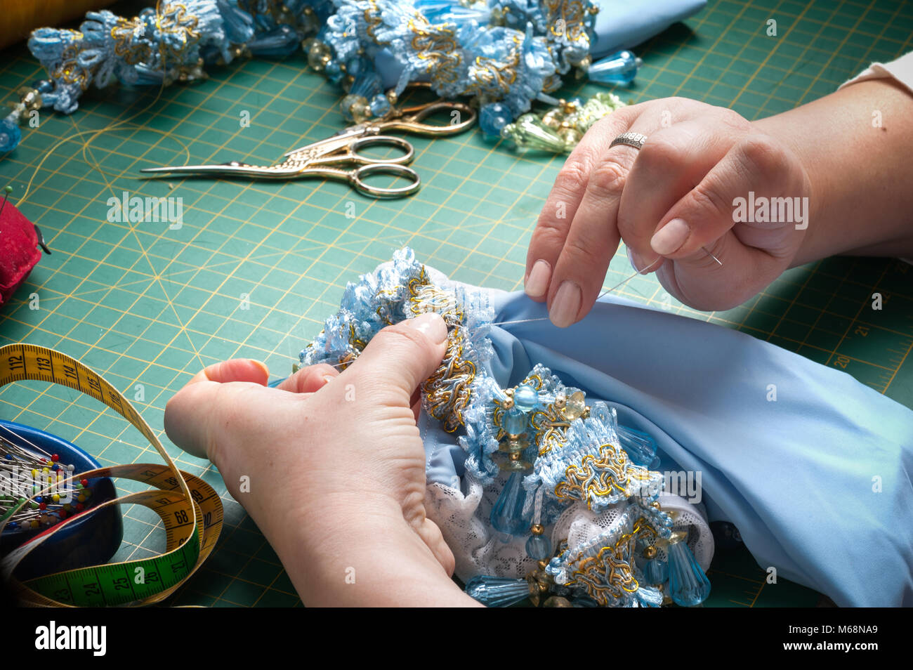A woman sews a decorative element to clothes with a needle Stock Photo ...