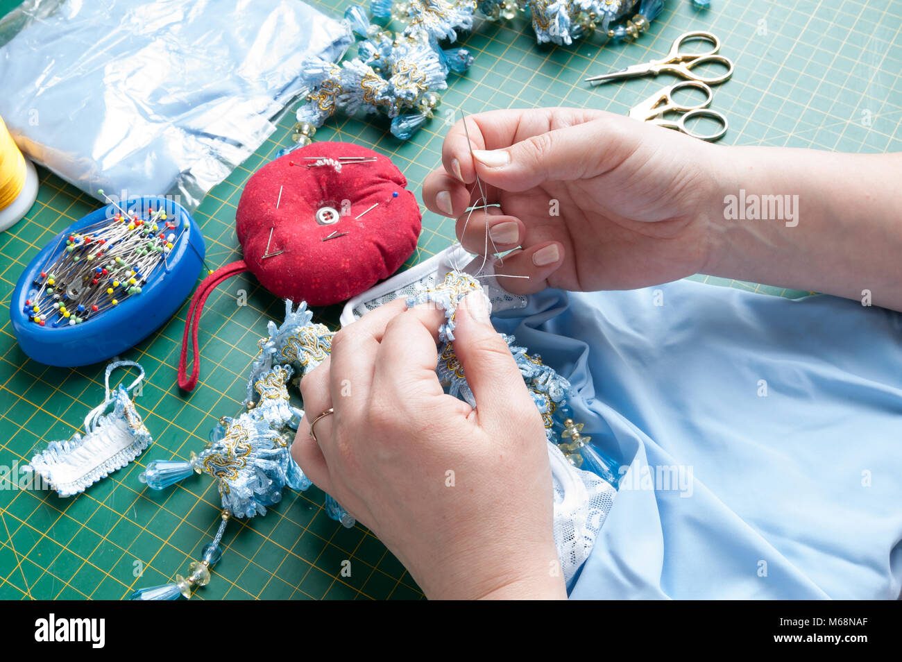 A woman sews a decorative element to clothes with a needle Stock Photo ...