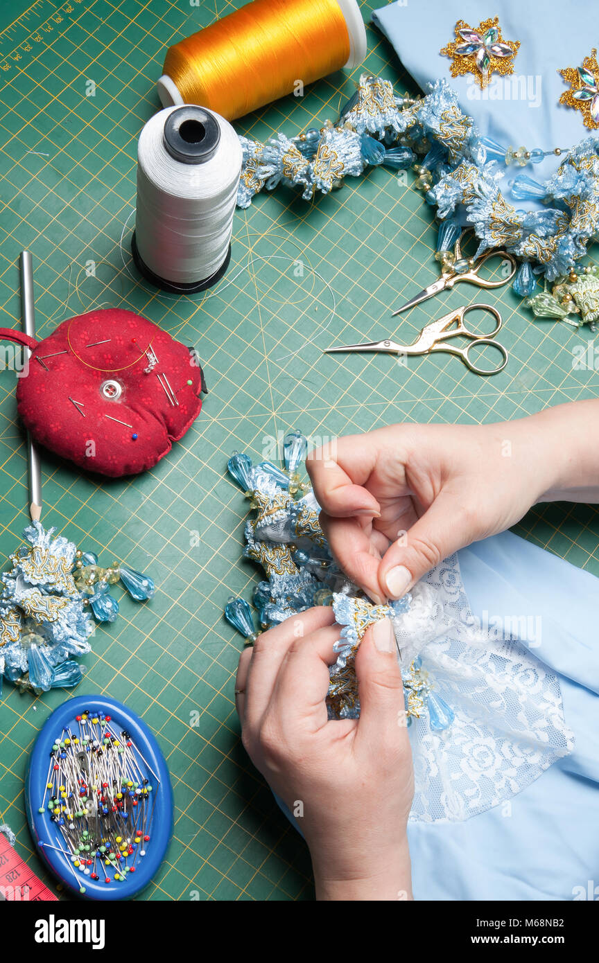 A woman sews a decorative element to clothes with a needle Stock Photo ...