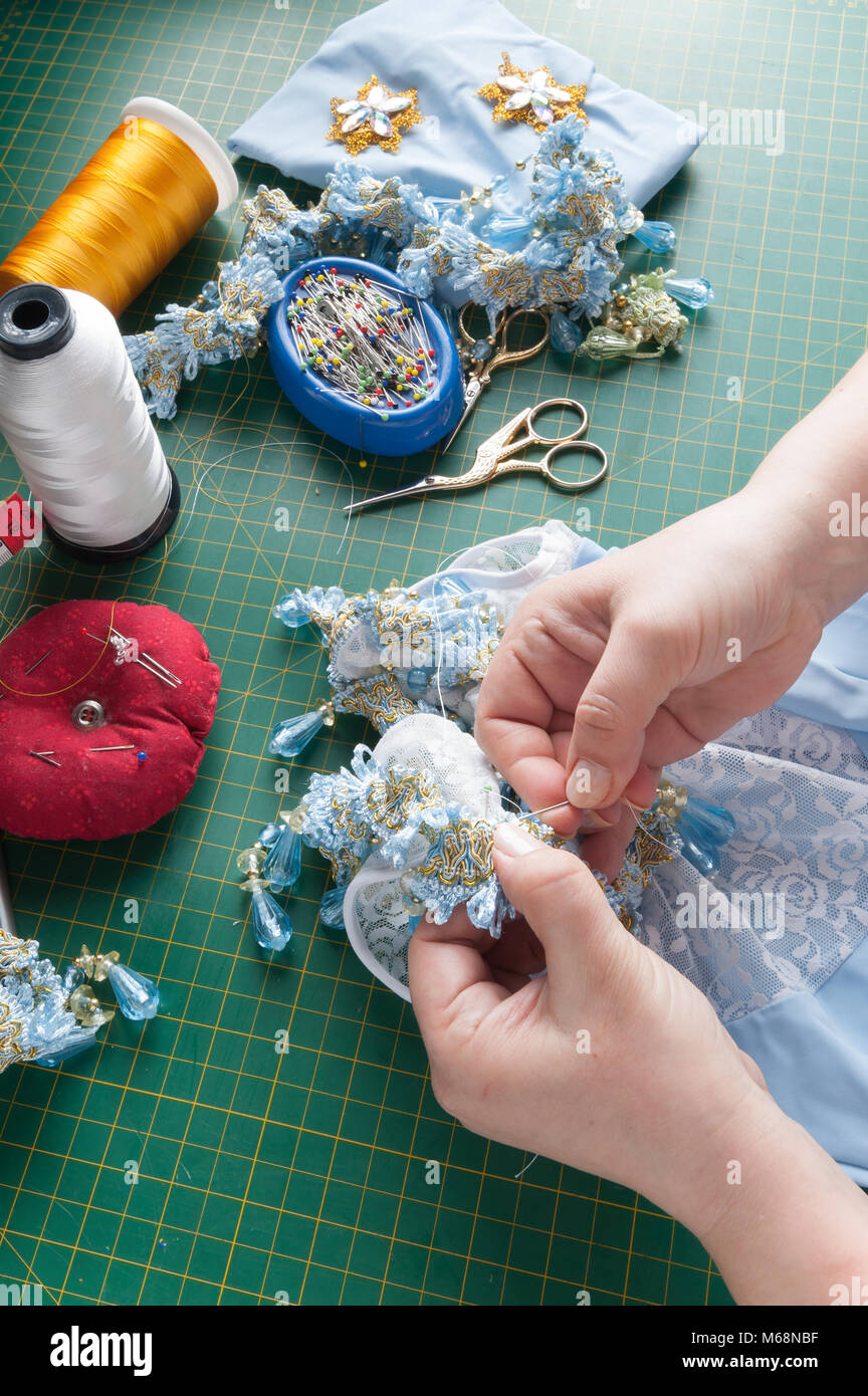 A woman sews a decorative element to clothes with a needle Stock Photo ...