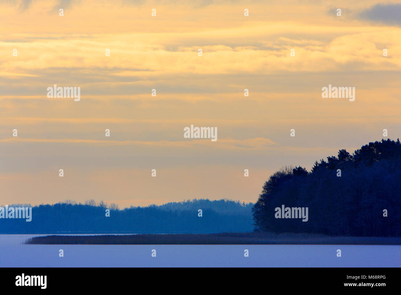 Winter landscape with frozen lake surface and woods in Masuria lakes ...