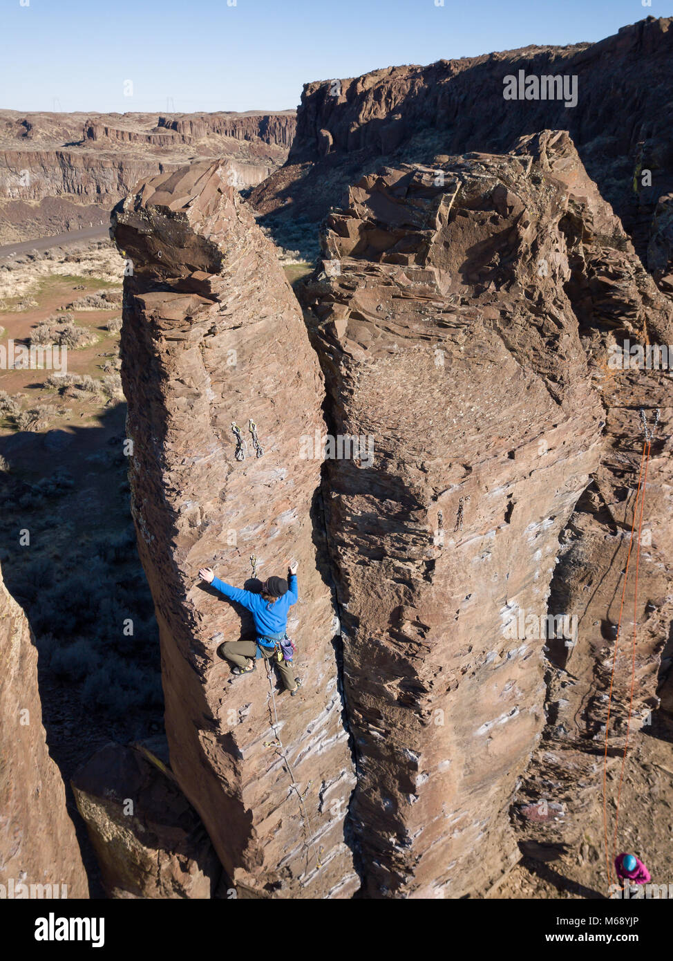 Aerial view of a rock climber climbing a steep cliff during a sunny ...
