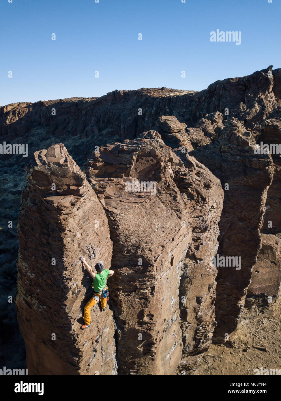 Aerial view of a rock climber climbing a steep cliff during a sunny ...