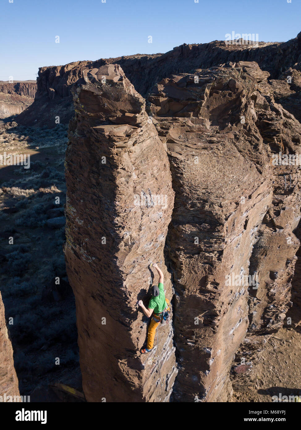 Aerial view of a rock climber climbing a steep cliff during a sunny ...