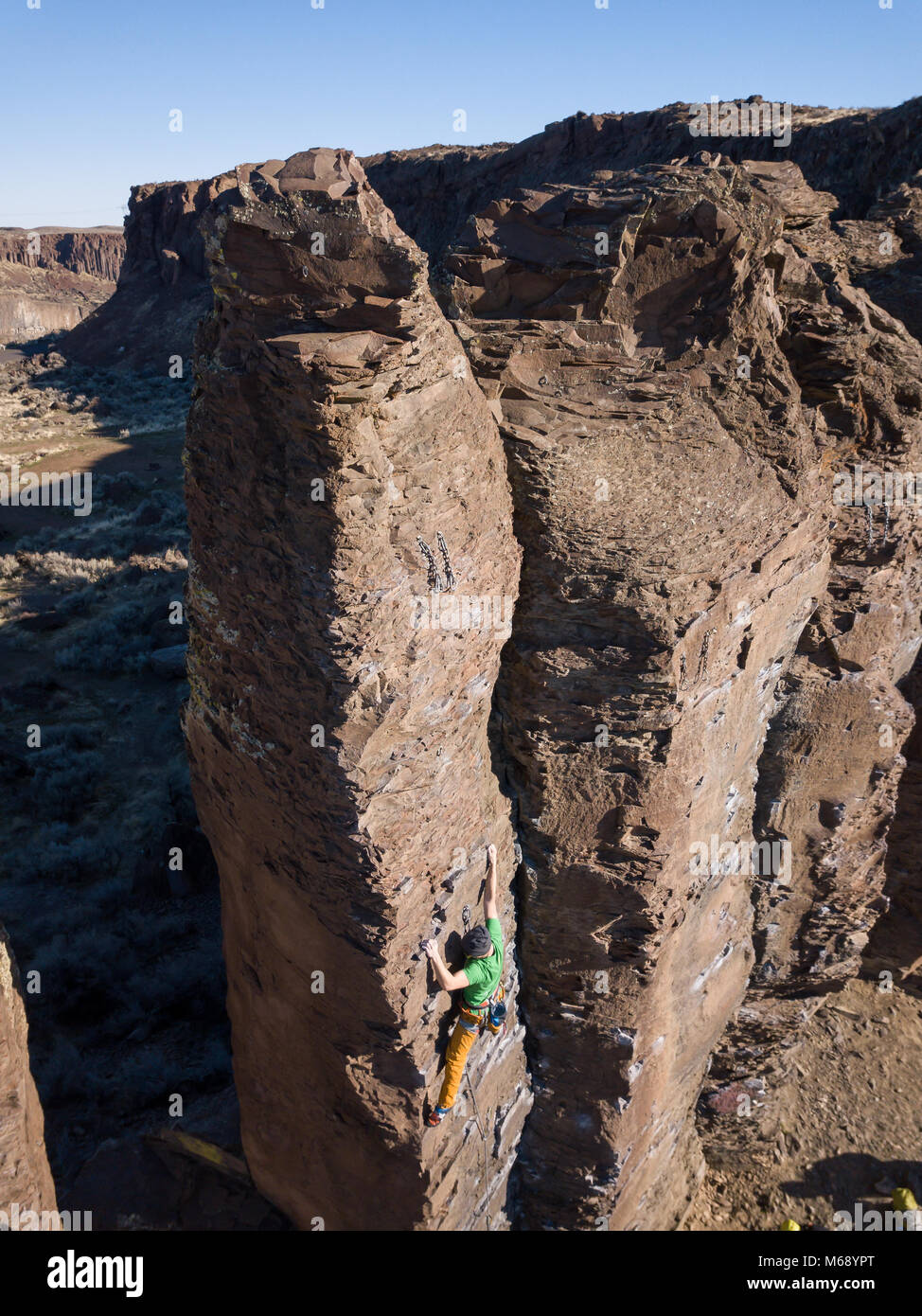 Aerial view of a rock climber climbing a steep cliff during a sunny ...