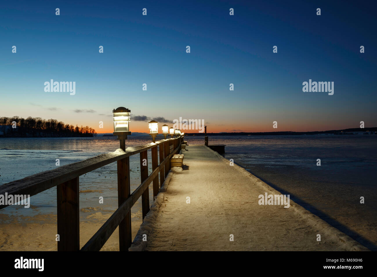 Jetty with snow and lights at sunset Stock Photo - Alamy