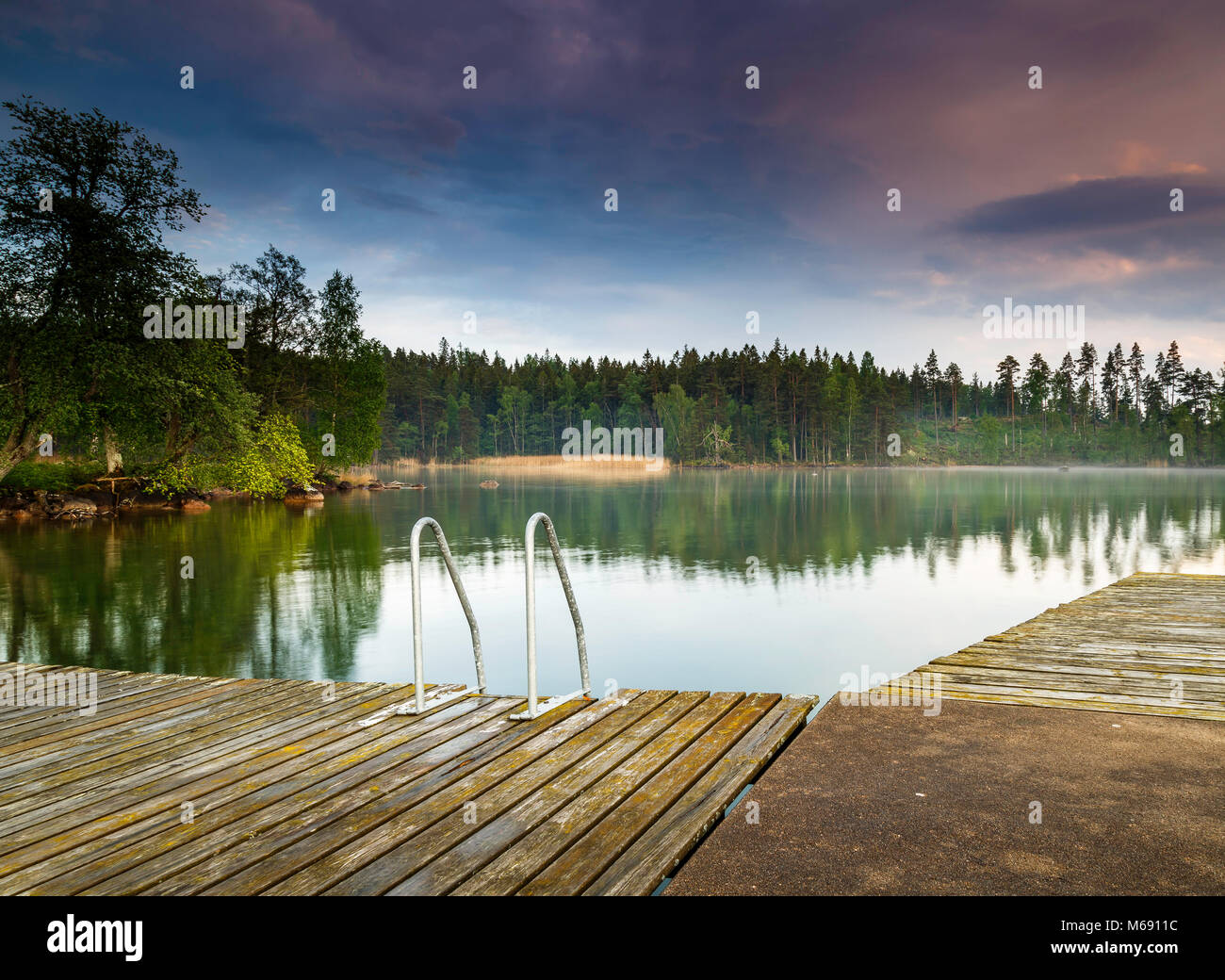 jetty with ladder at a little lake with forest around Stock Photo - Alamy