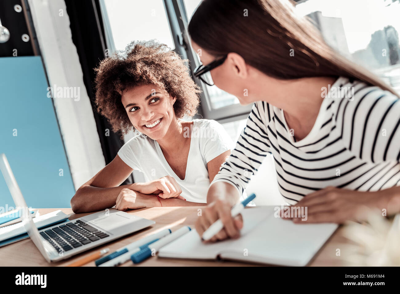Nice positive woman looking at her colleague Stock Photo - Alamy