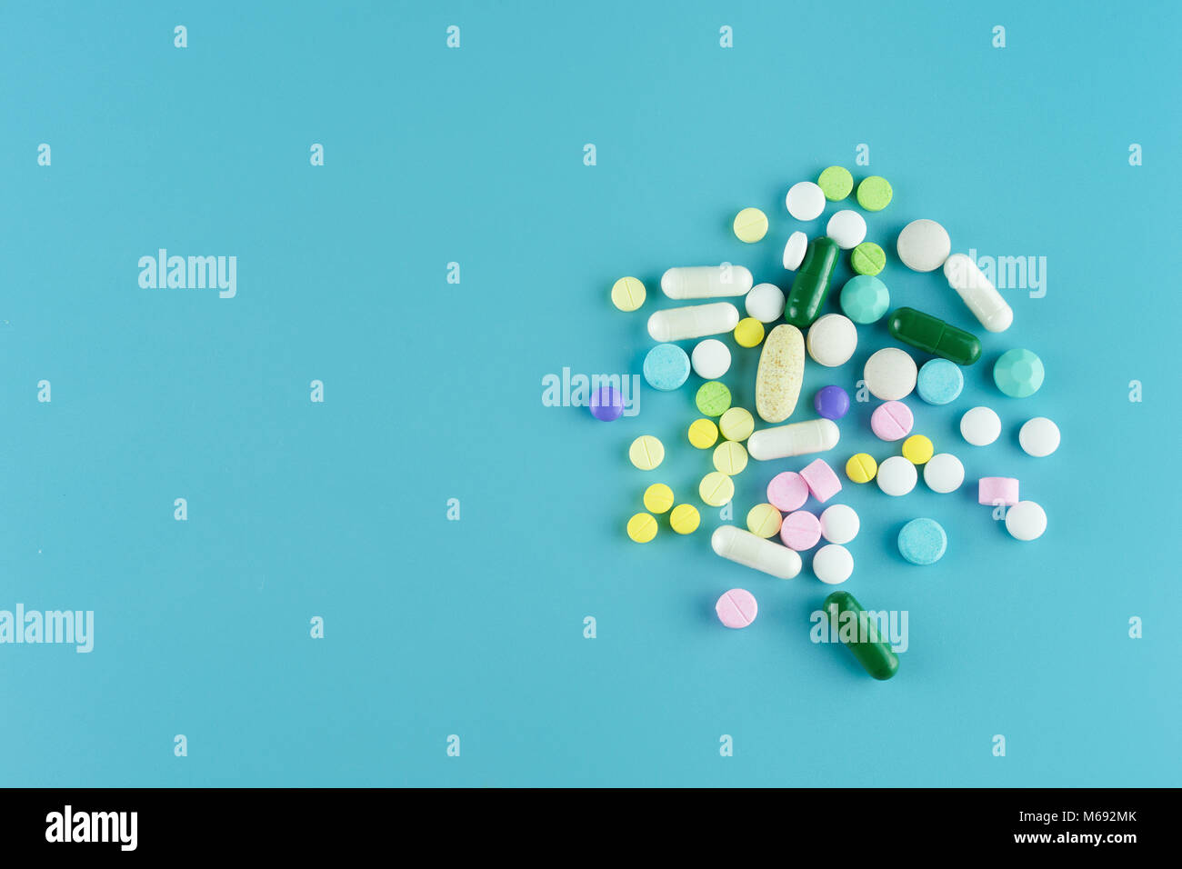 Assorted pharmaceutical medicine pills, tablets and capsules on blue ...