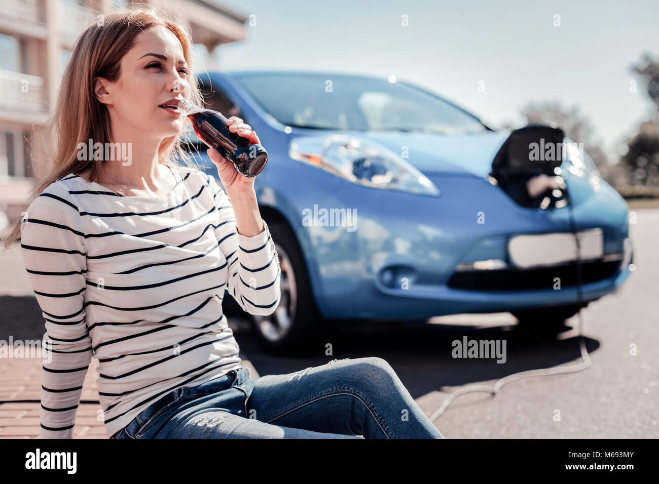Pretty calm woman sitting and drinking cola Stock Photo - Alamy
