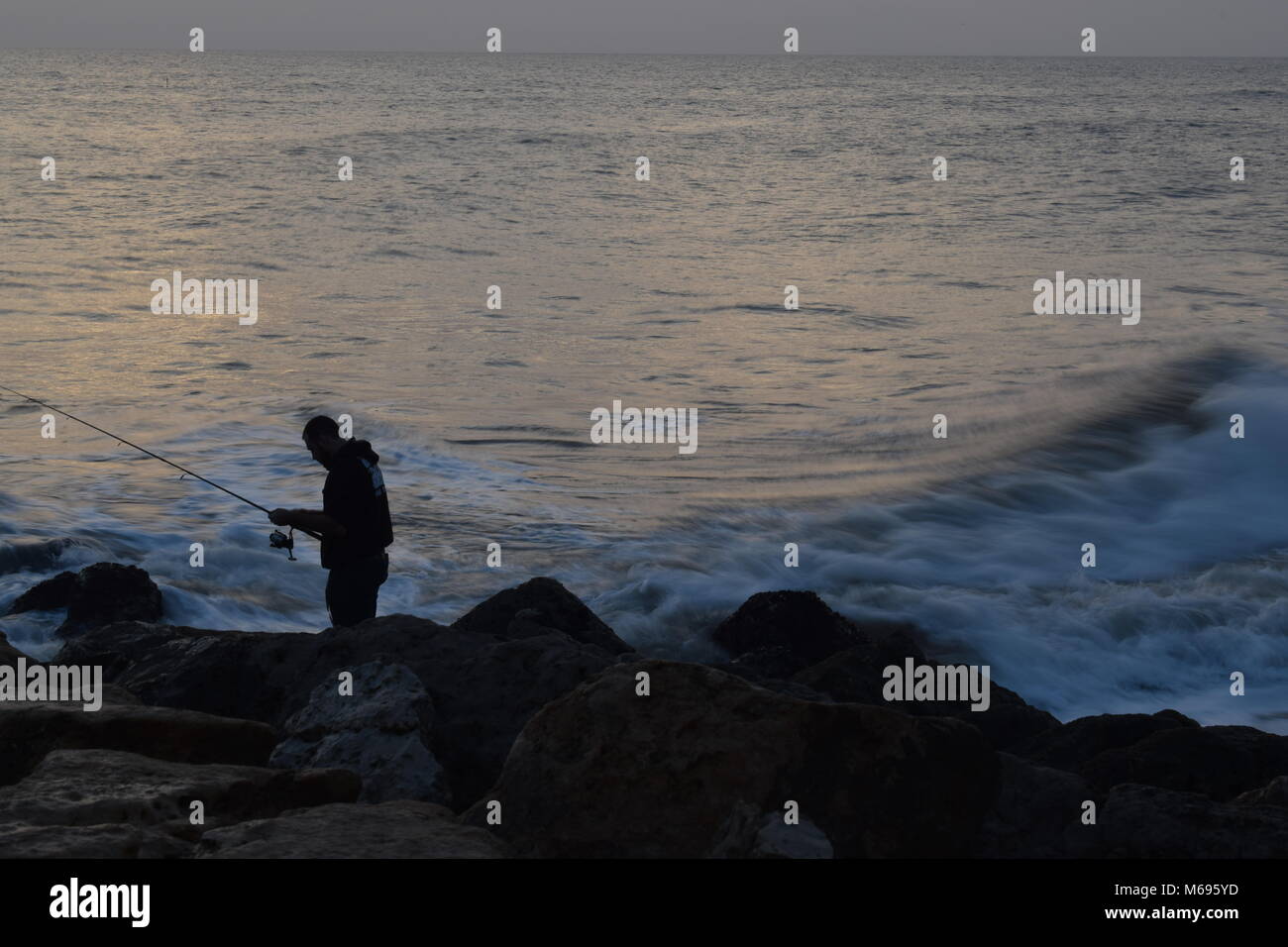 Man fishing on the rocks in Portugal Stock Photo - Alamy