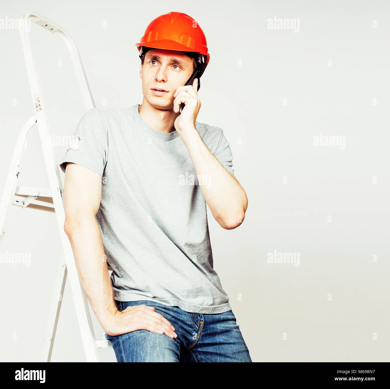 young real hard worker man isolated on white background on ladder ...
