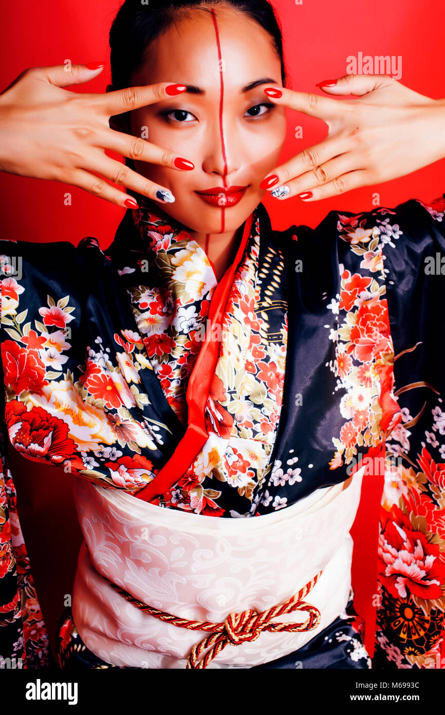 young pretty geisha on red background posing in kimono, oriental people ...