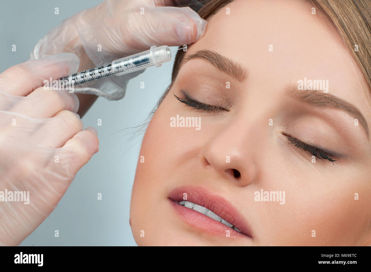 Woman is getting filler injection over eyebrow. Anti-aging treatment ...