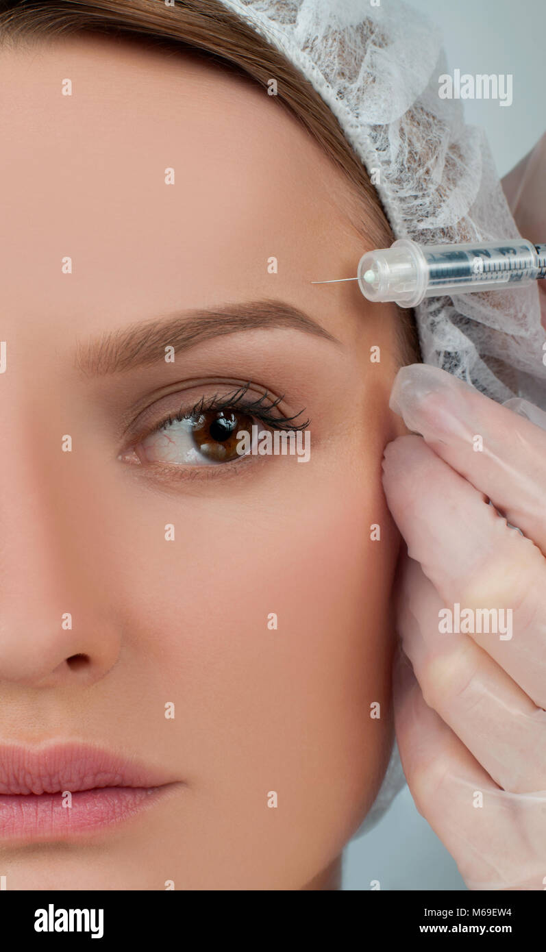 Woman is getting filler injection over eyebrow. Anti-aging treatment ...