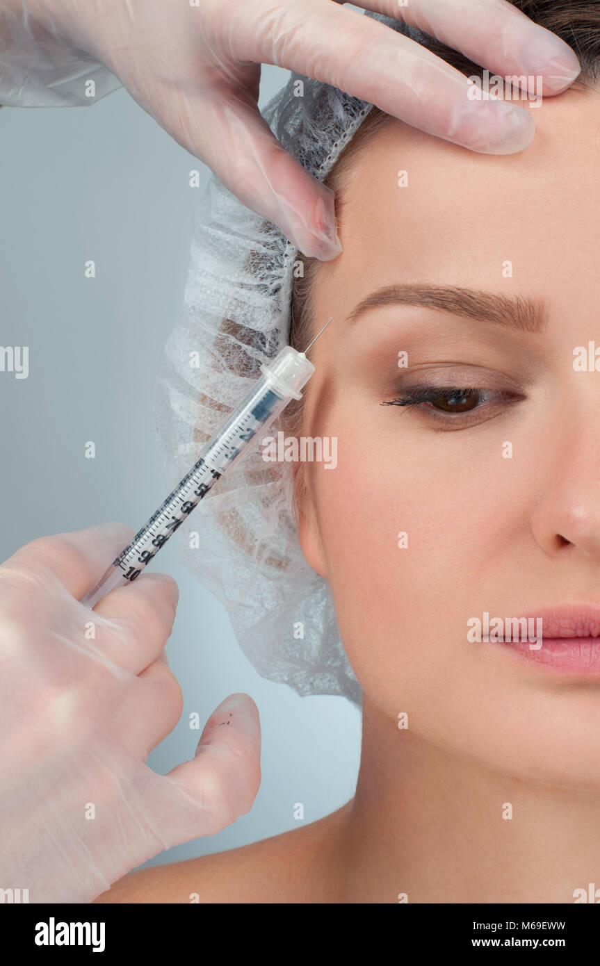 Woman is getting filler injection over eyebrow. Anti-aging treatment ...