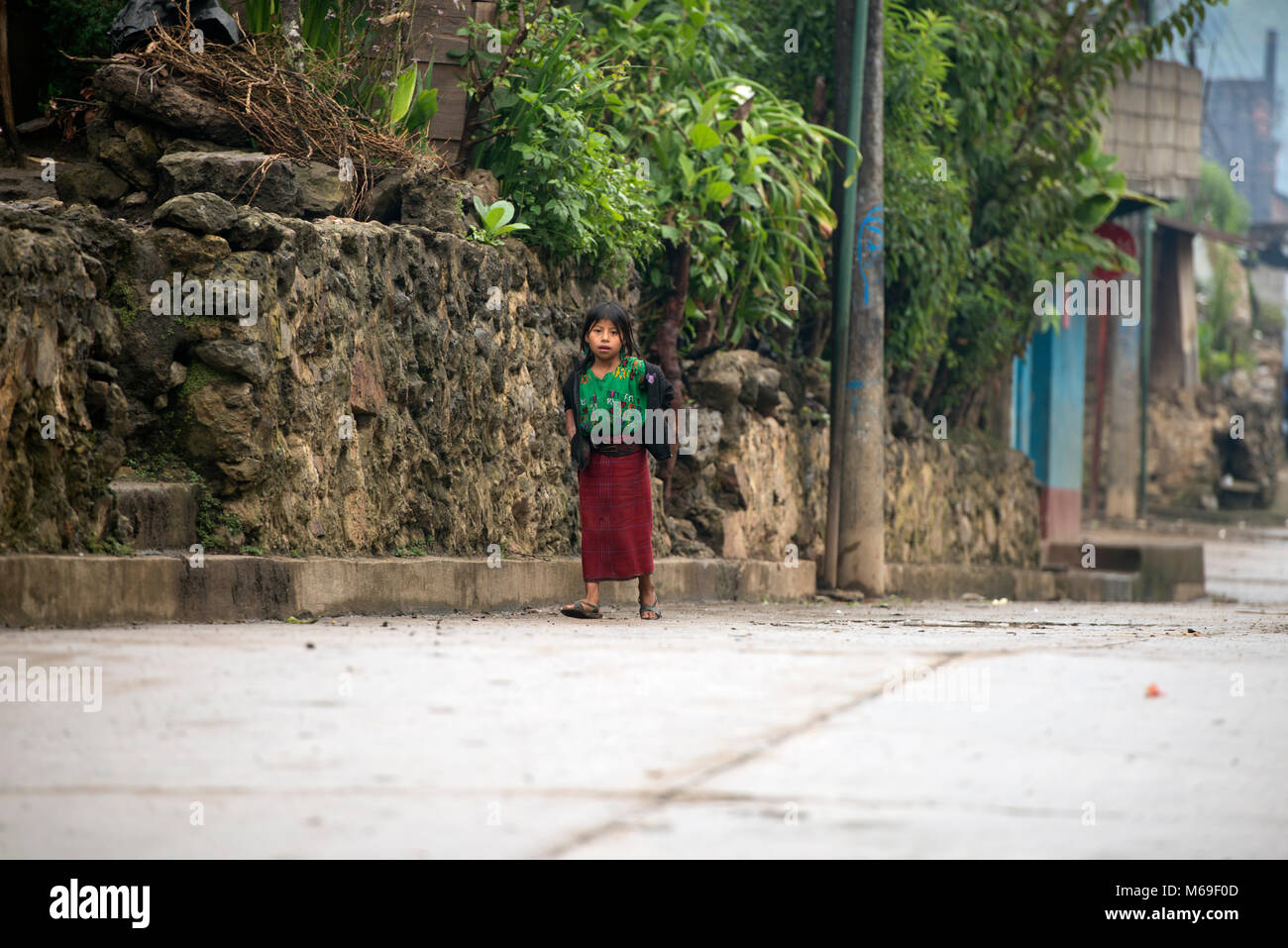 A young, indigenous Ixil Maya girl in traditional dress walking along ...