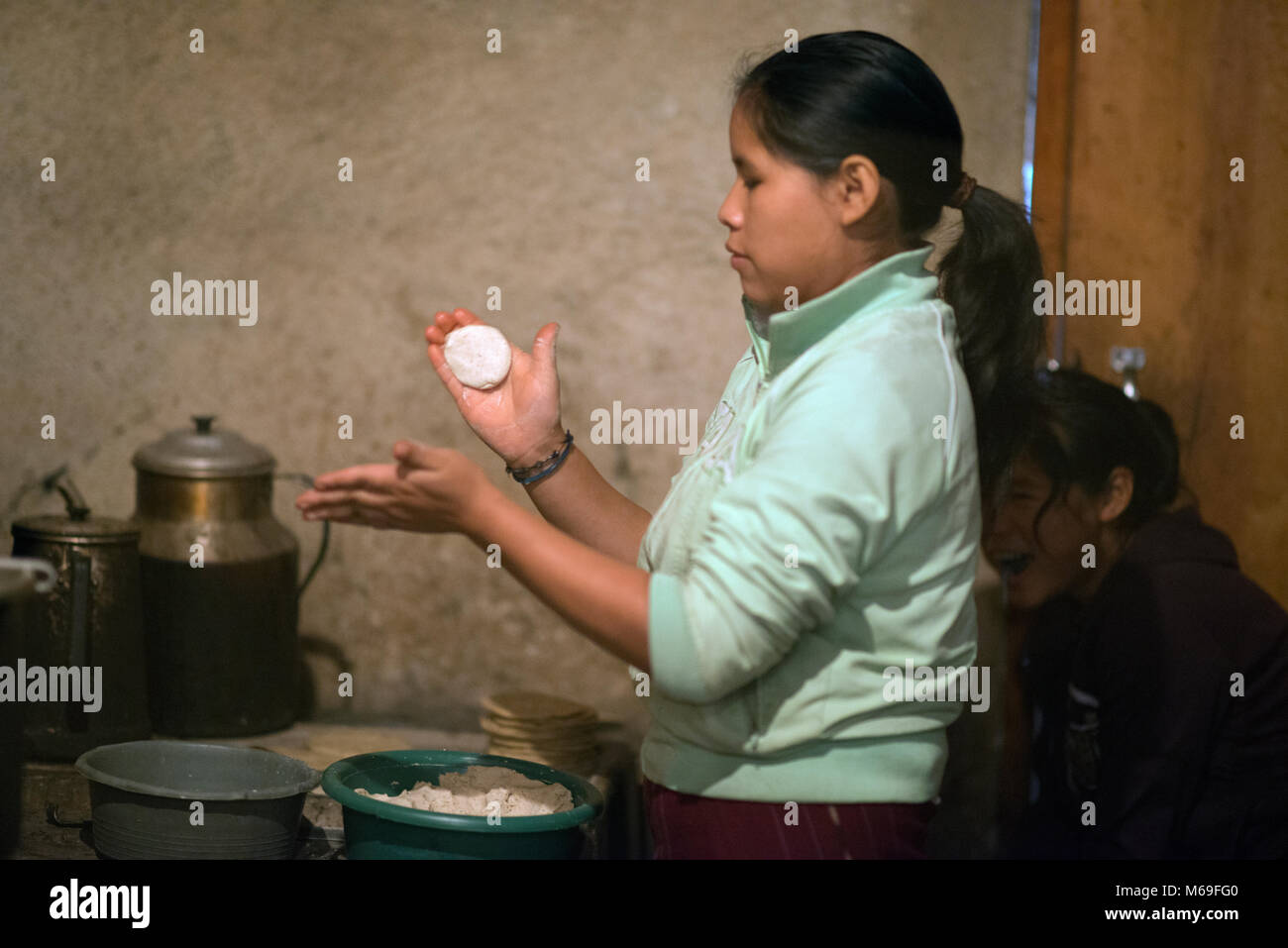 A young ethnic indigenous Ixil Maya woman making a tortilla in her cafe ...