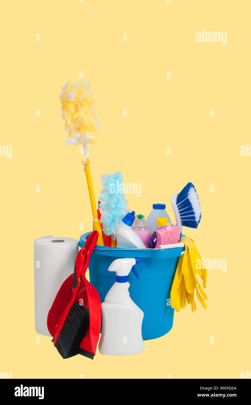 Variety of cleaning products in a bucket on pastel yellow background ...