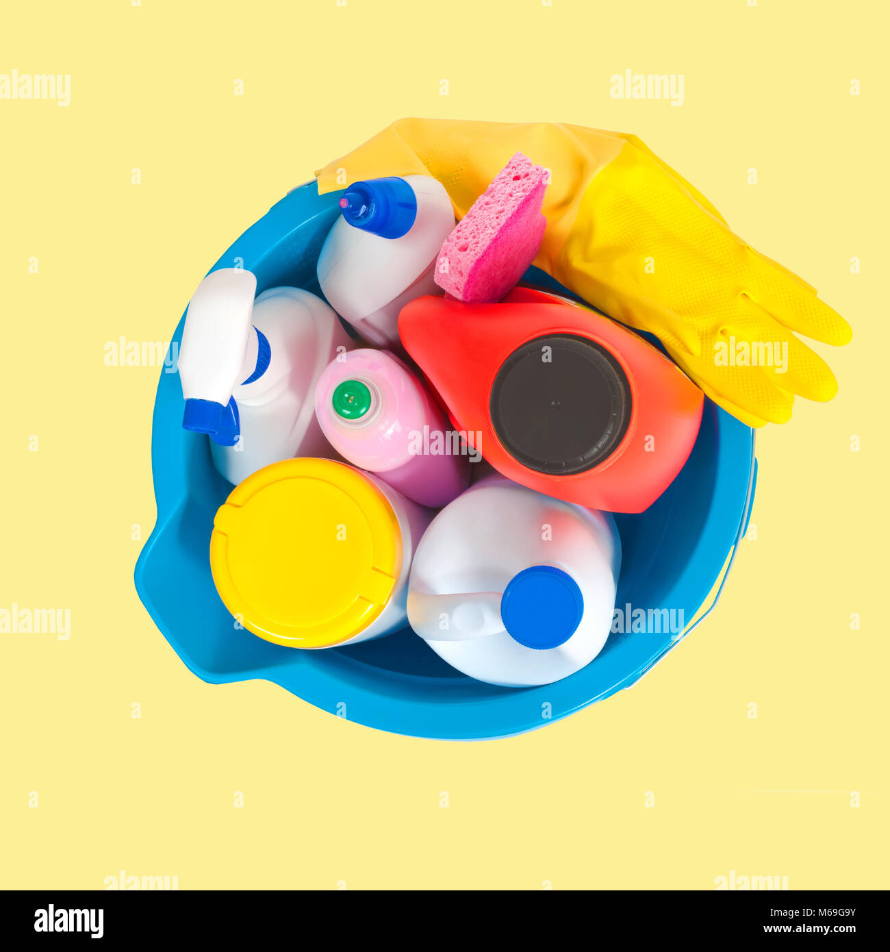 Variety of cleaning products in bucket on pastel yellow background ...