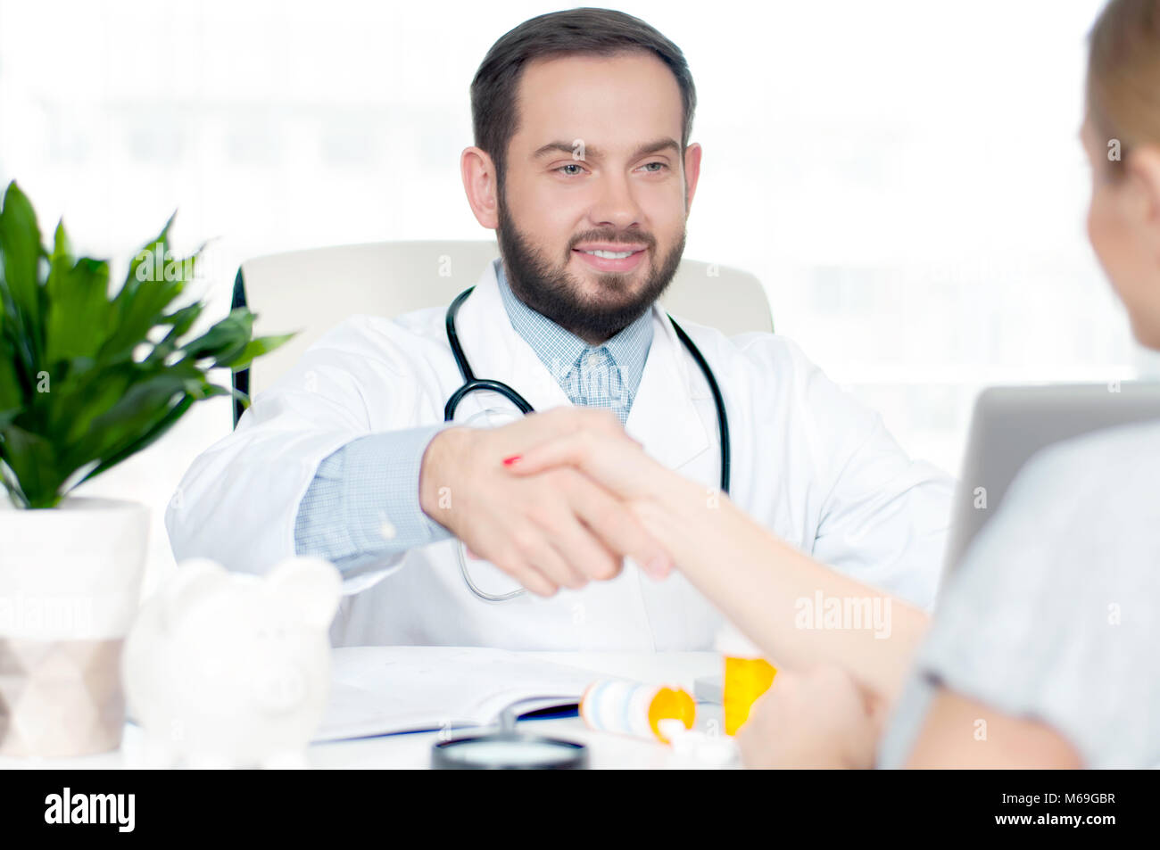 Doctor and patient. Smiling doctor shaking hands with a female patient ...
