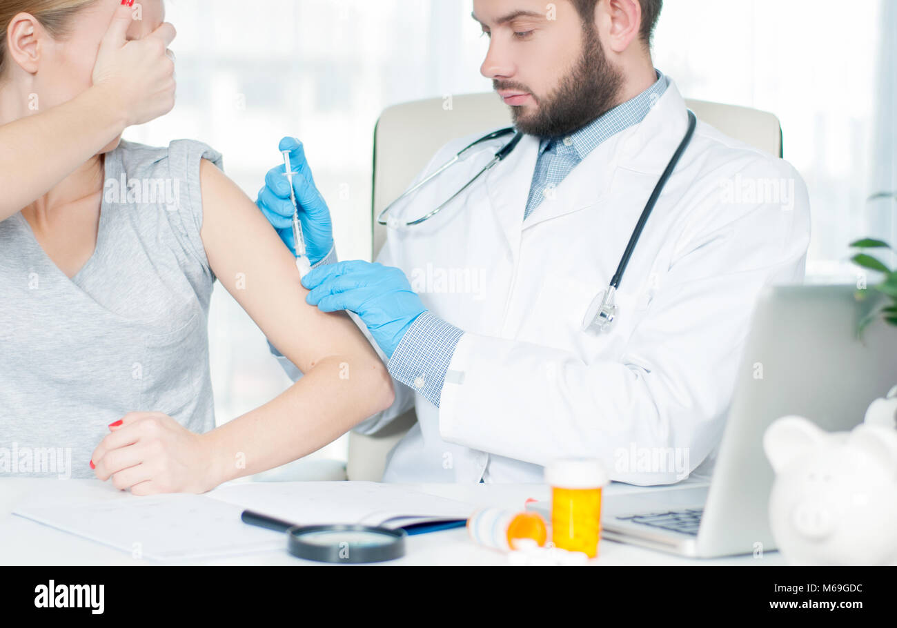 Vaccination. Flu shot. Doctor with syringe making vaccination to ...