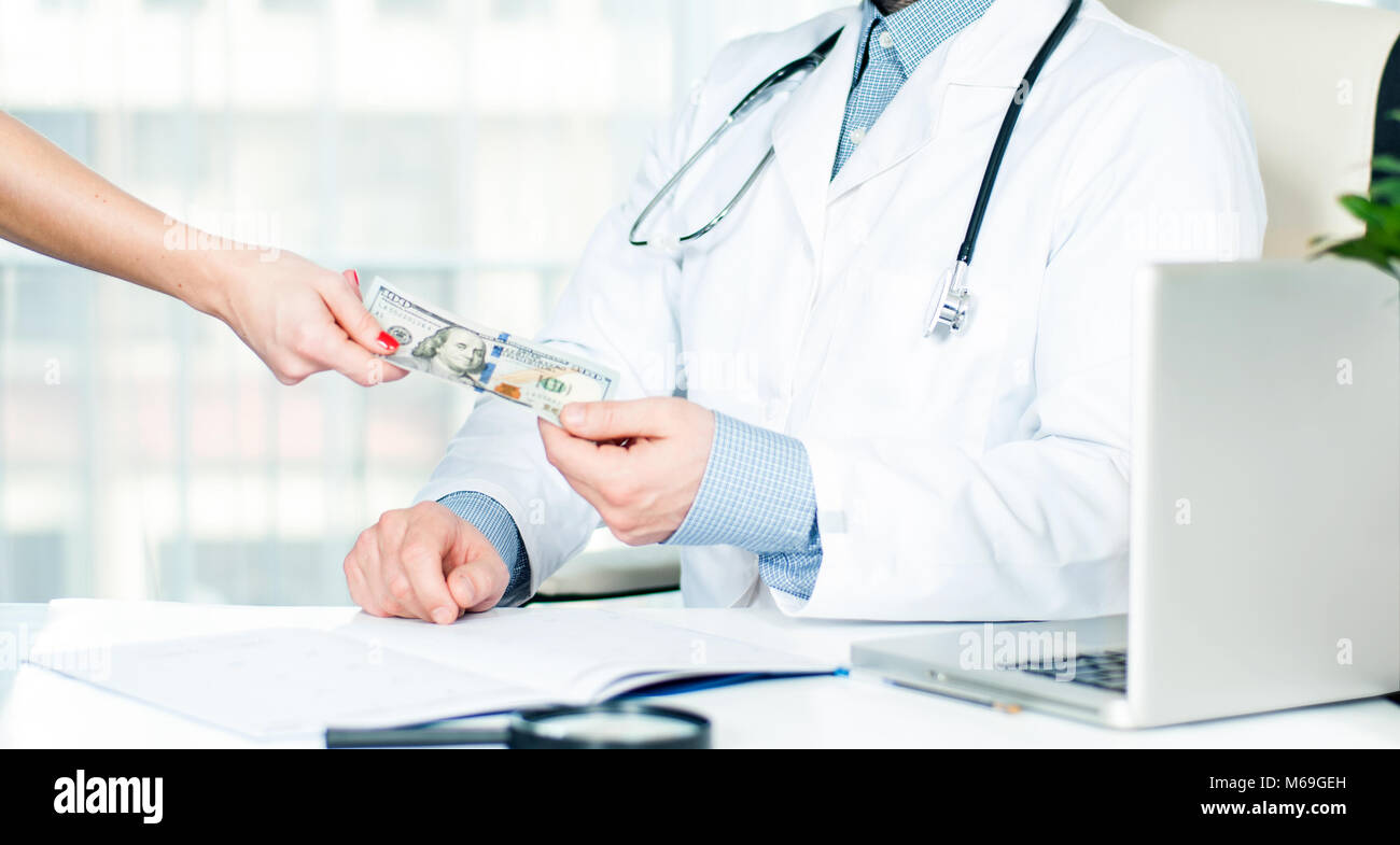 Patient giving money to doctor. Doctor taking hundred dollars Stock ...