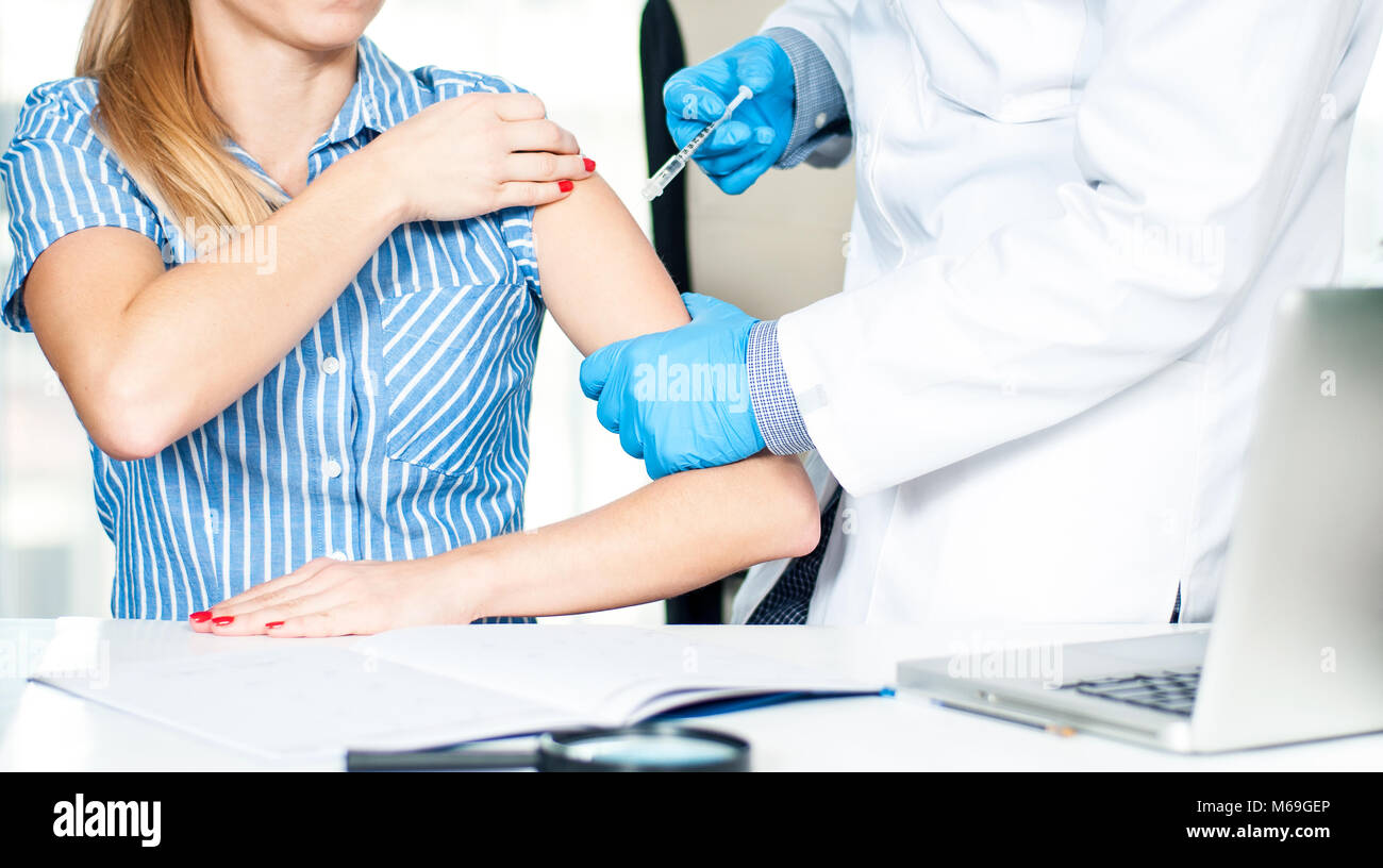Vaccination. Flu shot. Doctor with syringe making vaccination to ...