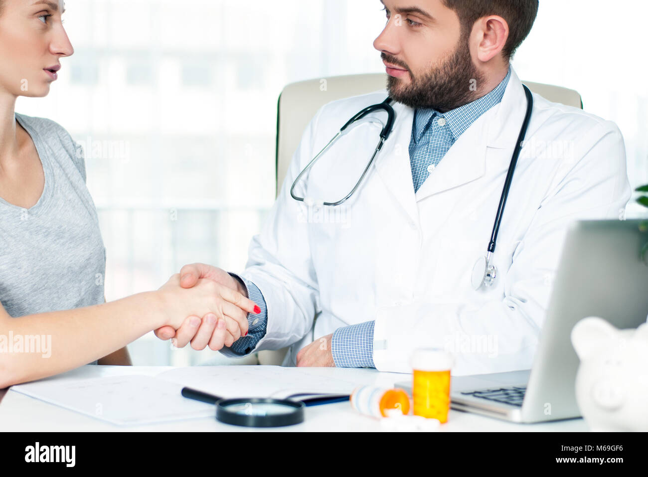 Doctor and patient. Smiling doctor shaking hands with a female patient ...