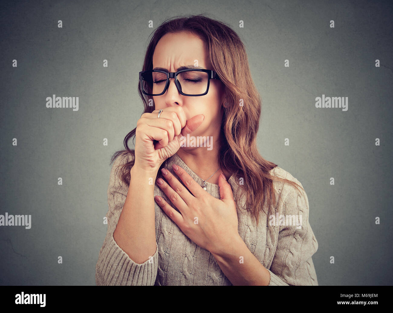 Young woman having asthma problems and coughing badly covering mouth ...