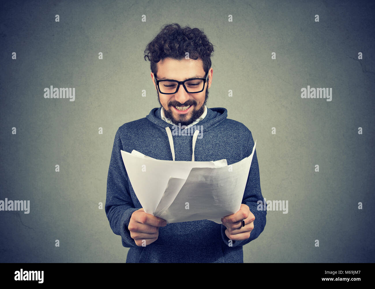 Young happy casual man looking through documents and happy with gained ...