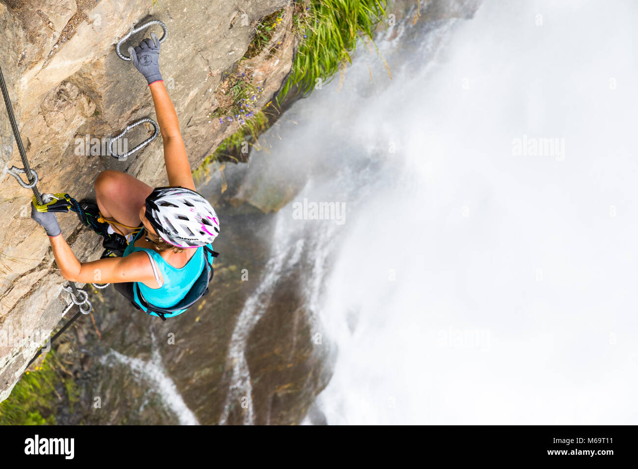 A female climber hanging by a cliff over the Stuibenfall waterfall in ...