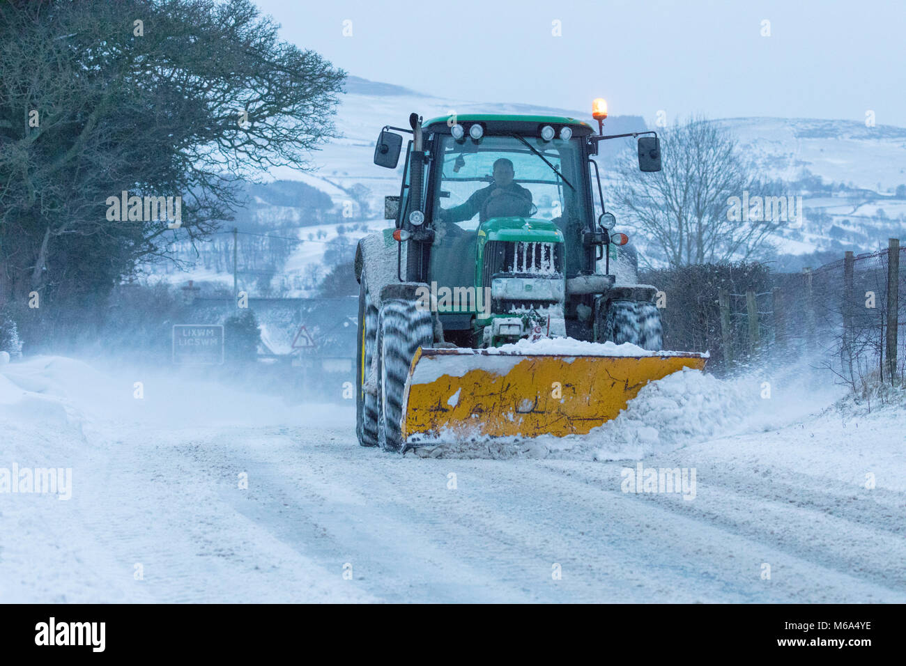 A local farmer with a snow plough attached to the front of his tractor ...