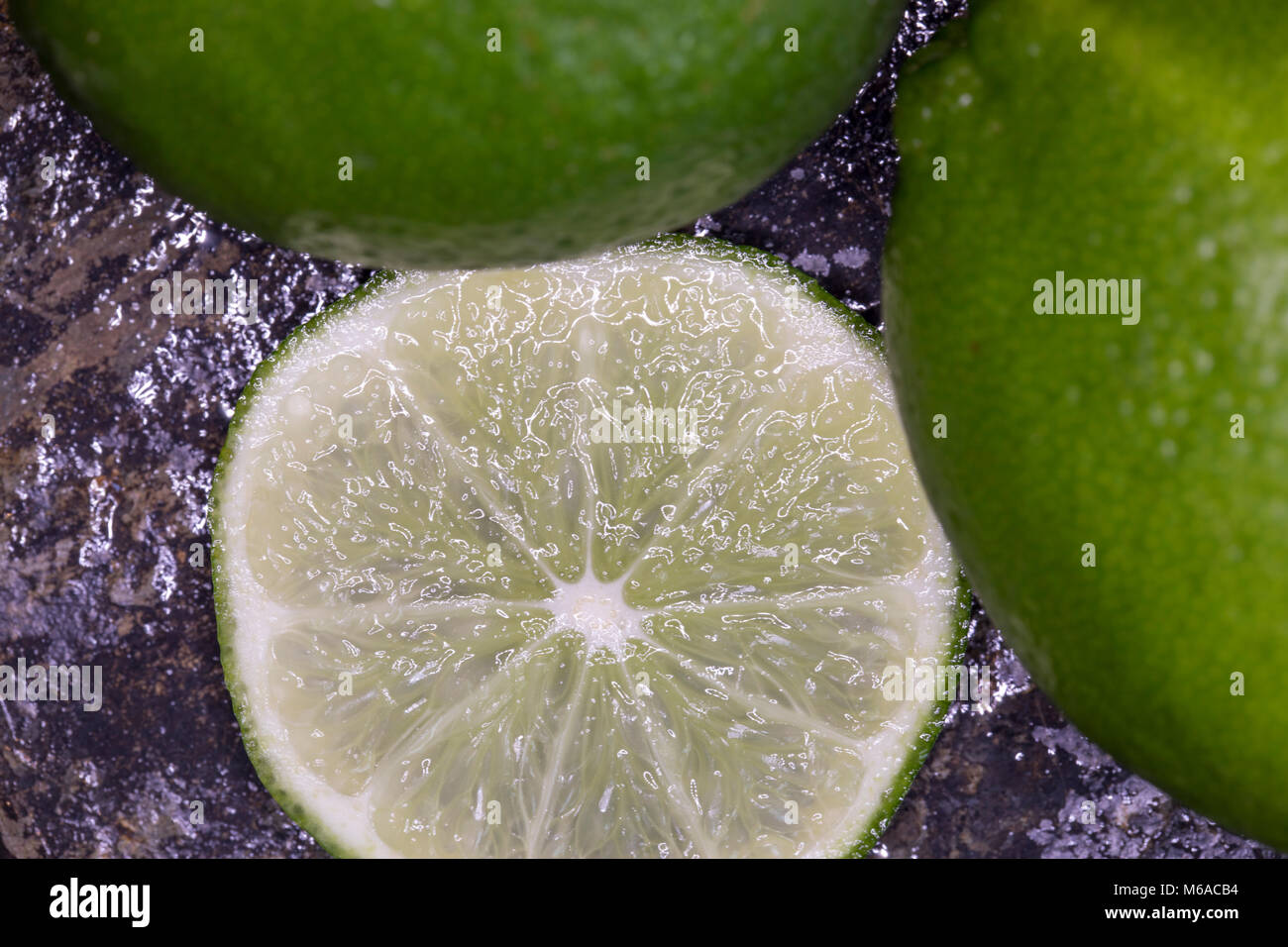Close up of lime slice with fresh whole limes on granite Stock Photo ...