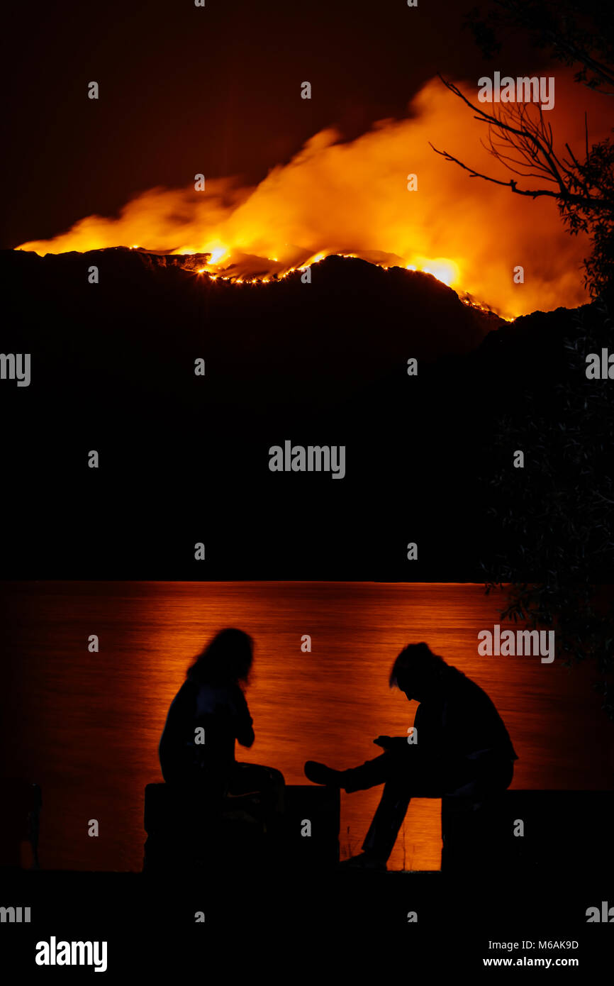 Silhouette of two women watching Forest Fire. Night fire in the forest ...