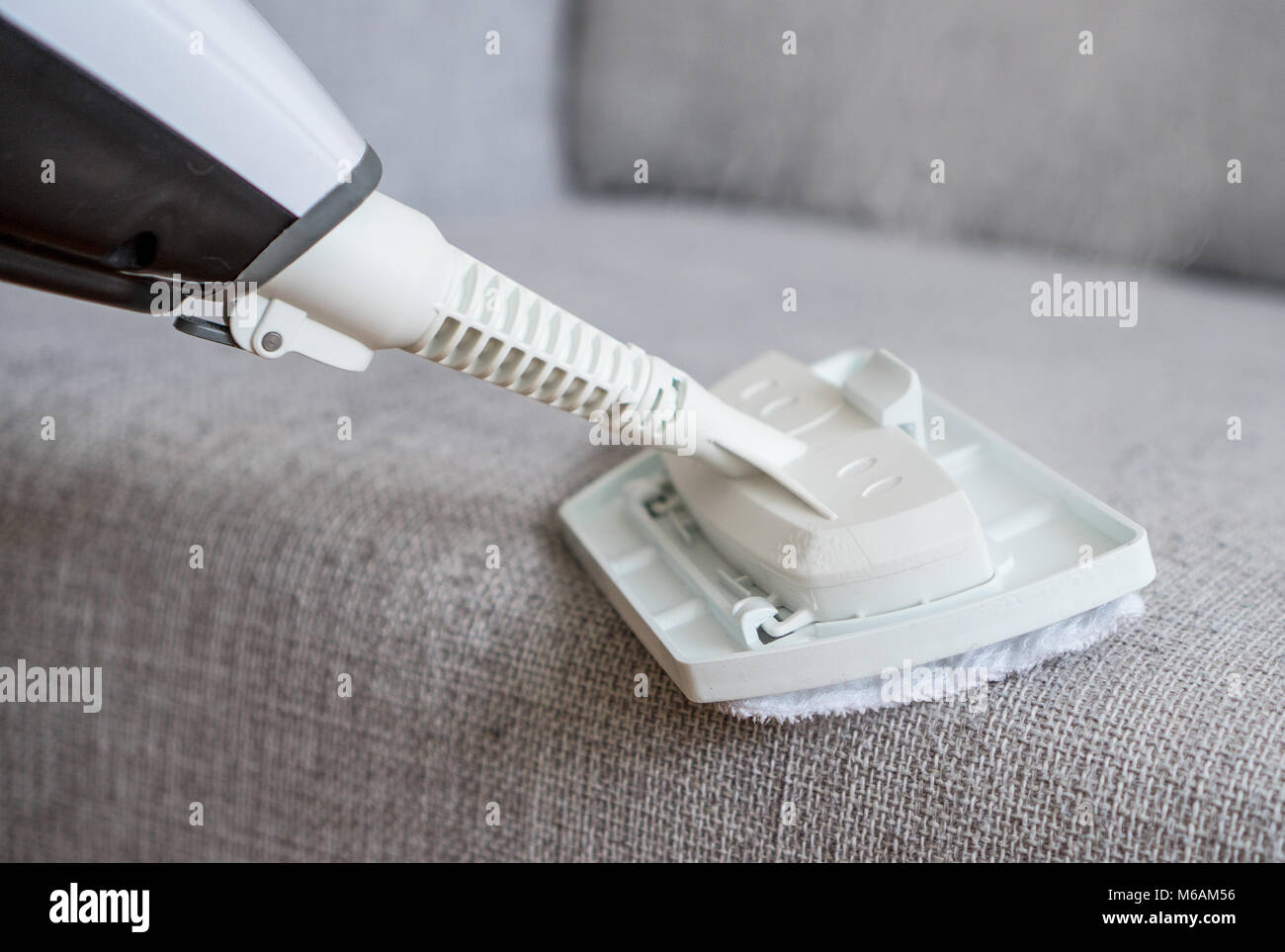 Cleaning fabric of the sofa with a steam cleaner Stock Photo - Alamy