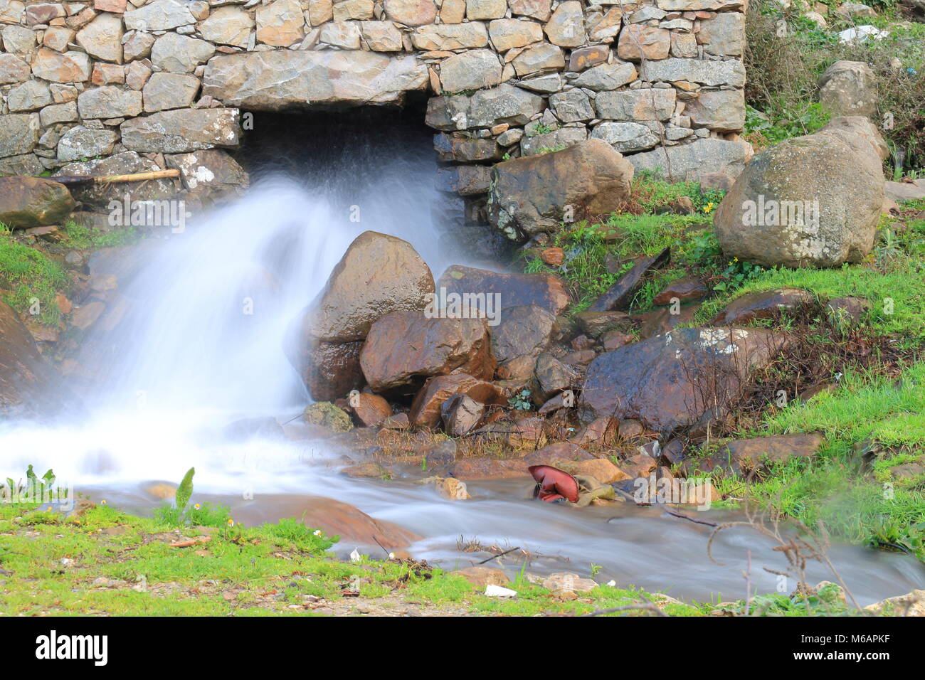 Water stream coming out of a traditional old water mill in full ...